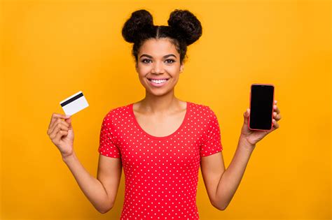 긍정적 인 쾌활한 미국 소녀 힙스터 프로모터 홀드 핸드폰 직불 카드 추천 쉬운 뱅킹 온라인 결제 착용 빨간 점선 티셔츠 밝은