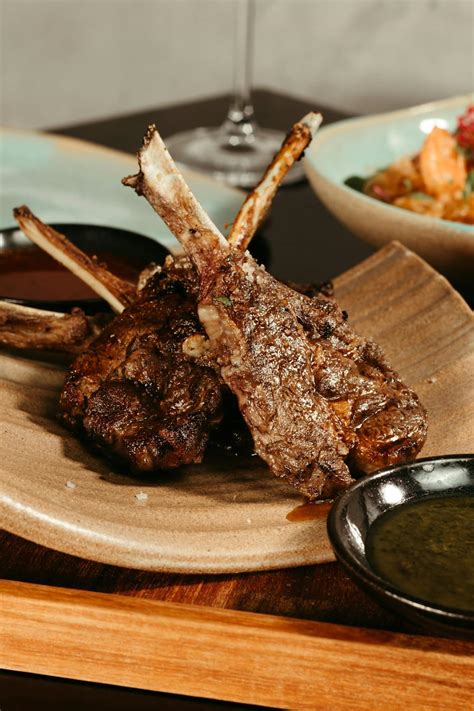 갈색 고기 고명 그릴 다육 단백질 도자기 접시 딥핑 소스 레스토랑 레스토랑 장면 로즈마리 맛있는 맛있는 식사 먹는 목조 테이블 미식가 보르 바