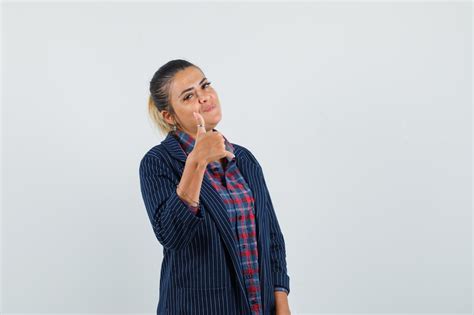 Леди показывает палец вверх в рубашке куртке и выглядит уверенно вид спереди Бесплатное фото