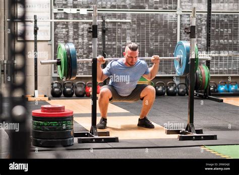 Full Body Of Determined Male Athlete In Sportswear Doing Back Squats With Heavy Barbell During