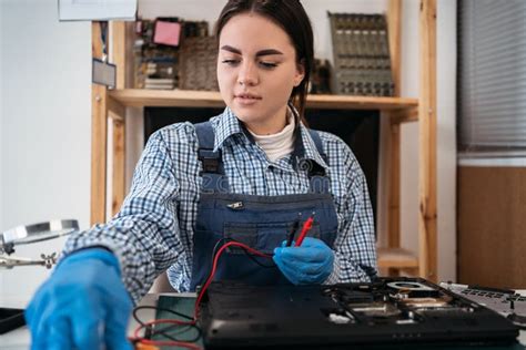 Female Worker Testing Laptop Motherboard Using Multimeter While Working In Repair Computers
