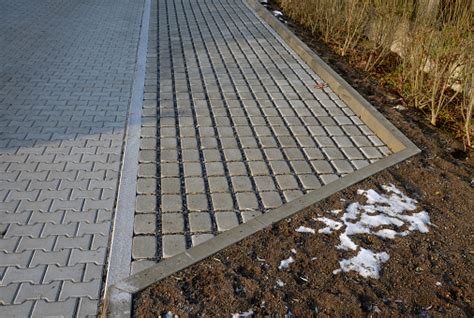 도시에 새로운 설립 된 거리 세로 주차장은 자갈로 가득 틈새 타일에 침투 회색 콘크리트로 만들어집니다 도로 충돌에서 물의 유출을 제한하는 조치 거리에 대한 스톡 사진 및