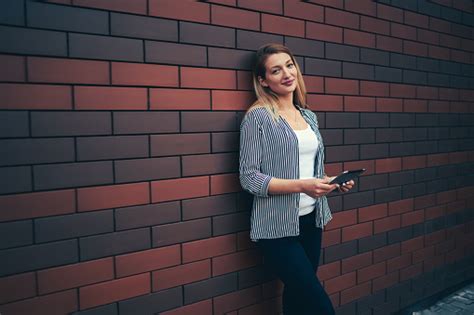 현대 장치 도시의 설정에서 자유 시간을 즐기면서 카메라 보고 아름 다운 젊은 여자의 반 길이 초상화 귀여운 긍정적인 Hipster 소녀 복사 공간 벽 근처의 거리에서 재현