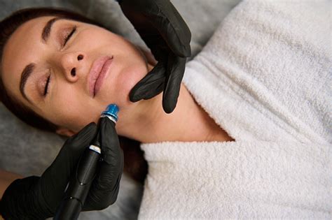 화장품 뷰티 스파 클리닉에서 얼굴 하이드로 미세 피부 마모 박리 치료를 받고 매력적인 중년 여성의 클로즈업 히드라 진공 청소기