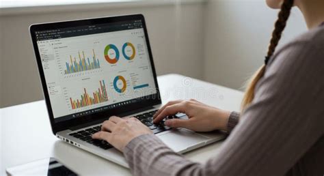 Female Analyzing Data On Laptop With Graphs And Charts In Office