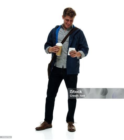 전체 길이한 사람1 인정면2029세 성인 잘생긴 사람 갈색 머리짧은 머리 백인 남성젊은 남자 앞에 서 흰색 배경시원한 태도 및 스마트폰을 사용 하 여 내려다 보고 후드티에