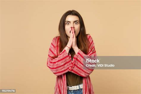캐주얼 옷 카메라를 보고 파스텔 베이 지 벽 배경에 고립 된 손으로 입을 덮고 있는 충격 젊은 여자의 초상화 사람들은 진심으로