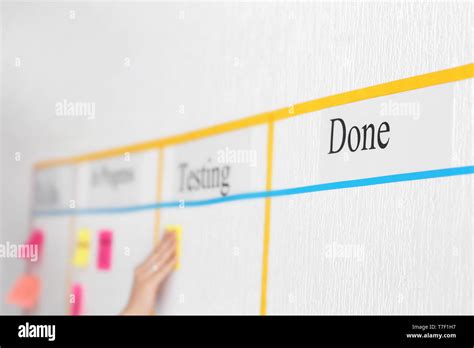 Woman Attaching Sticky Note To Scrum Task Board In Office Stock Photo Alamy