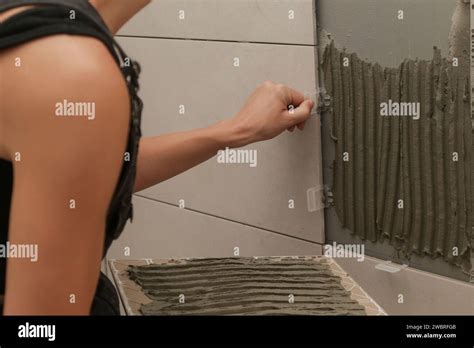 Woman Tiling Bathroom Walls Applying Adhesive On A Tile And Placing Ceramic Tile In Right