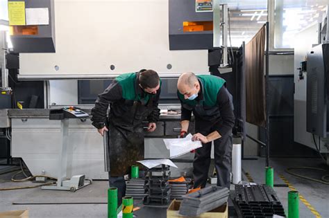 코로나바이러스 전염병으로 인해 보호 마스크를 쓰고 현대 공장에서 일하고 Cnc 기계를 위한 프로그램과 자료를 준비하는 두 명의