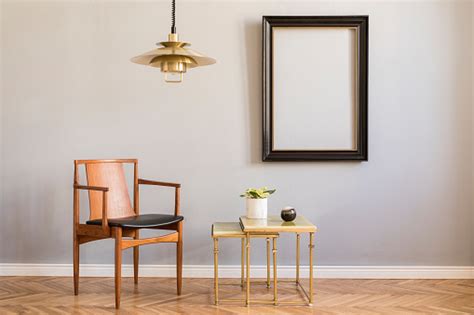 세련 되 고 디자인의 자 금 램프 식물이 있는 작은 테이블 레트로 인테리어 회색 배경 벽에 검은 모의 프레임 거실의 최소한의 개념입니다 실제 사진 인테리어 디자이너에 대한