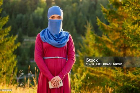 공원의 베일 배경 숲 나무로 덮인 파란 스카프 얼굴을 입은 녹색 눈을 가진 아름다운 무슬림 여성의 초상화 모로코 문화에 대한