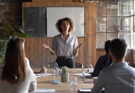 A Woman Stands In Front Of A Table With A Screen Behind Her Premium Ai Generated Image