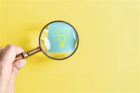 노란색 펀칭 종이의 전구 숨기기 성공적인 개발 혁신 아이디어 창의적 사고 방식 사고 개념에 대한 객관적인 목표에 대한 전구 아이콘 대상에 돋보기 초점을 잡는 손 승계 계획에