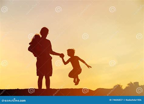 Padre Feliz Con El Hijo Y La Hija Que Saltan En La Puesta Del Sol
