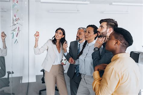 유리 벽에 차트를 작성하고 고집을 부림으로써 창조적 인 기업 사무실에서 작업 계획과 목표를 개발하는 공식적인 마모의 심각한