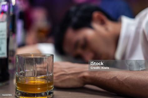 아시아 우울증 남자는 마음이 상하고 술집에서 맥주를 마시는 느낌 카운터 바에 앉아 외로움을 느끼는 술 한 병을 들고 나이트 클럽에서 혼자 술에 취해 숙취를 느끼는 매력적인
