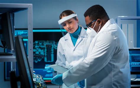 Group Of Microelectronic Engineers Discussing In A Modern Microprocessor Manufacture Lab