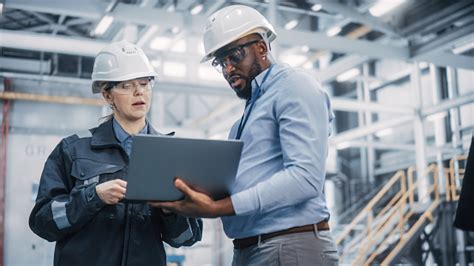 안전 유니폼을 입고 노트북 컴퓨터에서 작업 하드 모자를 착용 두 가지 전문 중공업 엔지니어 아프리카계 미국인 기술자와 여성