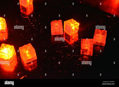 Red Glowing Ice Cubes Are Located On A Black Glossy With Water Drops Plastic Things Made In The