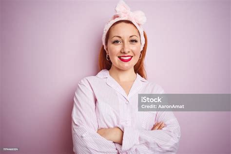 분홍색 고립 된 배경 행복 한 얼굴 카메라를 보고 교차 된 팔 미소 에 서 잠옷을 입고 젊은 아름 다운 빨간 머리 여자 긍정적 인 사람 긍정적인 감정 표현에 대한 스톡 사진