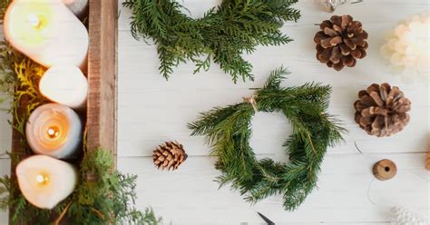 양초 솔방울 가위 장식품이 있는 소박한 크리스마스 화환이 흰색 나무 테이블에 놓여 있습니다 전나무와 삼나무 가지로 심플하고 세련된 크리스마스 화환 만들기 휴일