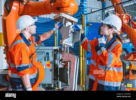 Engineer Team Worker Working With Robot Arm Assembly Machine In Modern Engineer Team Worker Working With Robot Arm Assembly Machine In Modern