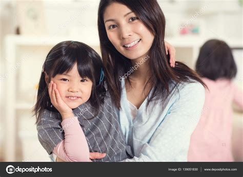 Portrait Of Happy Japanese Mother Hugging With Her Cute Little D