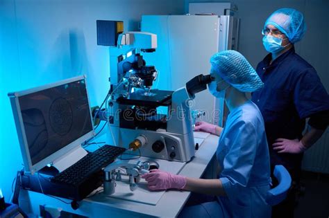 scientists using a microscope and computer in a sterile laboratory