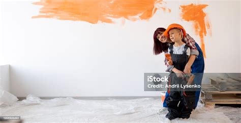 홈 수리 행복한 가족 엄마와 아들은 벽오렌지를 그렸습니다 벽 그림 리노베이션 또는 리모델링 룸 컨셉 헬멧을 쓰고 있는 여성과 어린이 아기에 대한 스톡 사진 및 기타 이미지