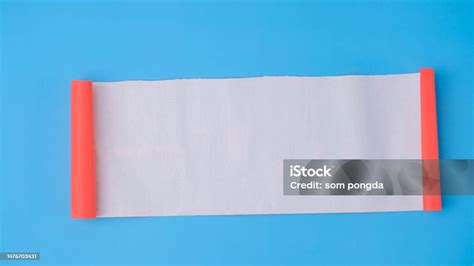 주황색 압연 사각형 용지가 연한 파란색 배경에 빈 흰색 시트로 펼쳐져 있습니다 텍스트 또는 광고 공간을 위한 복사 공간이 있는 구겨진 빈 백서 굴리기에 대한 스톡 사진 및