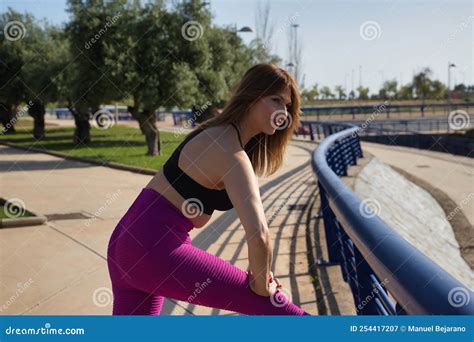 Mature Woman In Sportswear Doing Leg Stretches Leaning On A Railing