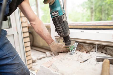 작업자의 강한 남성 손은 설치하고 Pvc 창을 해결하기 위해 벽돌 벽에 구멍을 만드는 도움으로 자신의 손에 전기 천공 드릴을 개최합니다 창문에 대한 스톡 사진 및 기타