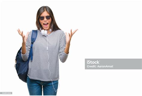 통해 헤드폰과 배낭을 착용 하는 젊은 아시아 학생 여자 배경 축 하 하는 미친 절연 및 팔 제기 성공을 위한 놀라게 했 고 눈을 흥분 비명 우승자 개념 배낭에 대한 스톡