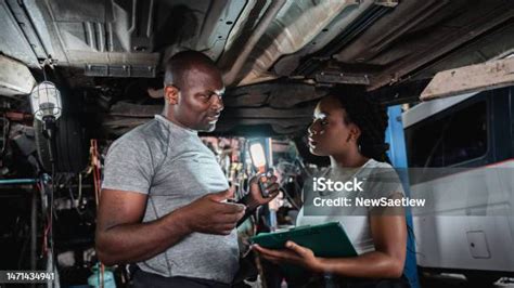 두 명의 정비사가 차고에서 자동차 아래 부품을 검사하고 체크리스트합니다 수리 자동차 서비스 개념 검사 보기에 대한 스톡 사진 및