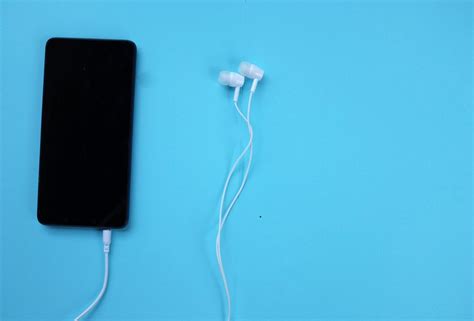 Premium Photo Smartphone Plugged In With White Headphones On A Blue Background