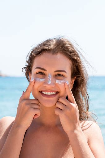 Tanned Woman Protects Her Face With Sun Cream From Sunburn At The Beach