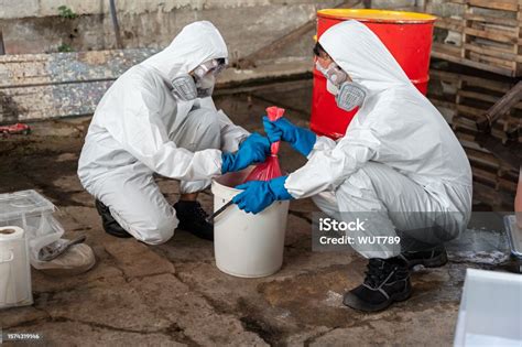 Ppe 슈트와 방독면을 착용한 두 명의 화학자로 구성된 팀이 공장 창고 바닥에서 치명적인 화학 물질 유출을 회수합니다 산업 플랜트에서 화학 물질 유출의 올바른 처리 18
