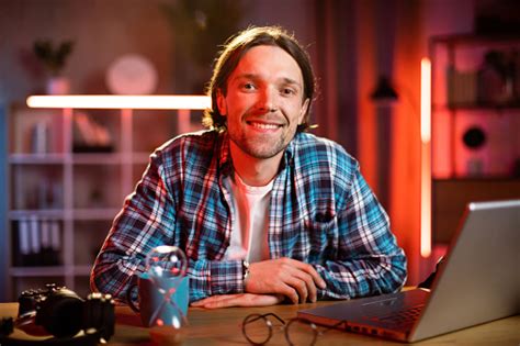 책상에 앉아 가슴에 손을 얹고 카메라를 바라보는 매력적인 남자 30 34세에 대한 스톡 사진 및 기타 이미지 30 34세 가정 생활 거실 Istock