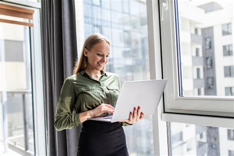 사무실에 서서 창문 근처에서 노트북을 들고 있는 젊은 사업가 노트북에 대한 스톡 사진 및 기타 이미지 노트북 노트북 사용하기 명랑한 Istock