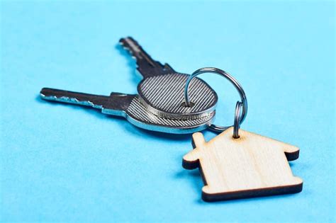 Premium Photo Trinket In The Form Of A Wooden House With The Keys To The Apartment On The Blue