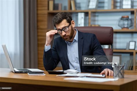 현대 사무실 내부의 서류 작업 뒤에 화가 난 사업가 재무 보고서 및 회계 문서를 읽고 결과에 만족하지 않고 성과에 실망한 수염을 가진 성숙한 남자 남자 사업가에 대한 스톡