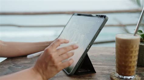 Female Freelancer Hands Drawing With Stylus On Tablet Ice Coffee On Table At Cafe With Ocean