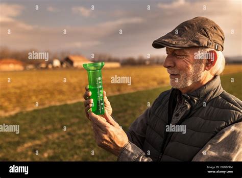 Senior Farmer Looking At Water Gauge For Rain Measuring In Field Stock Photo Alamy