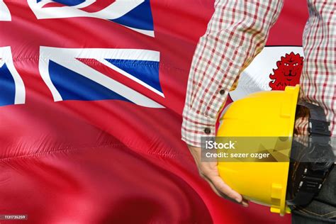 버 무 디안 엔지니어는 버뮤다 국기 배경을 흔들며 노란색 안전 헬멧을 들고 있다 건축 및 건축 개념 Bermuda Flag에 대한 스톡 사진 및 기타 이미지 Istock