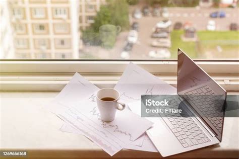 컵 커피 그래픽과 차트가 아파트 의 창가 근처 창턱에 누워 종이에 인쇄 된 노트북 원격 작업 개념 0명에 대한 스톡 사진 및 기타 이미지 Istock