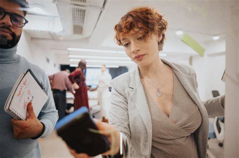 Young Colleagues In A Glass Walled Boardroom Collaborating Brainstorming And Strategizing On A