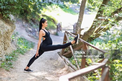 건강한 생활 방식을 선도하고 요가를 연습하는 젊은 임산부는 하누마 나사나 운동 세로 꼬기 따뜻한 여름 아침에 검은 색 스포츠 작업복을 입고 공원에서 훈련합니다 운동에 대한