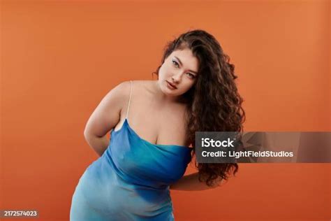 곱슬머리를 한 자신감 넘치는 몸매를 가진 여성이 활기찬 스튜디오 환경에서 아름답게 포즈를 취하고 있습니다 20 24세에 대한 스톡 사진 및 기타 이미지 Istock