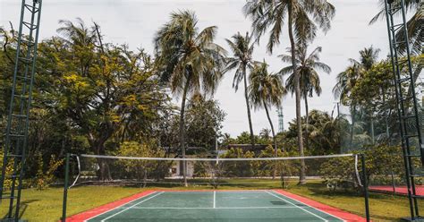 여름날 아늑한 배드민턴 코트의 광각 정면보기 땅에 표시가있는 빨간색과 녹색 필드 여러 야자수 측면에 조명 돛대 사진 Unsplash의 테니스 코트 이미지